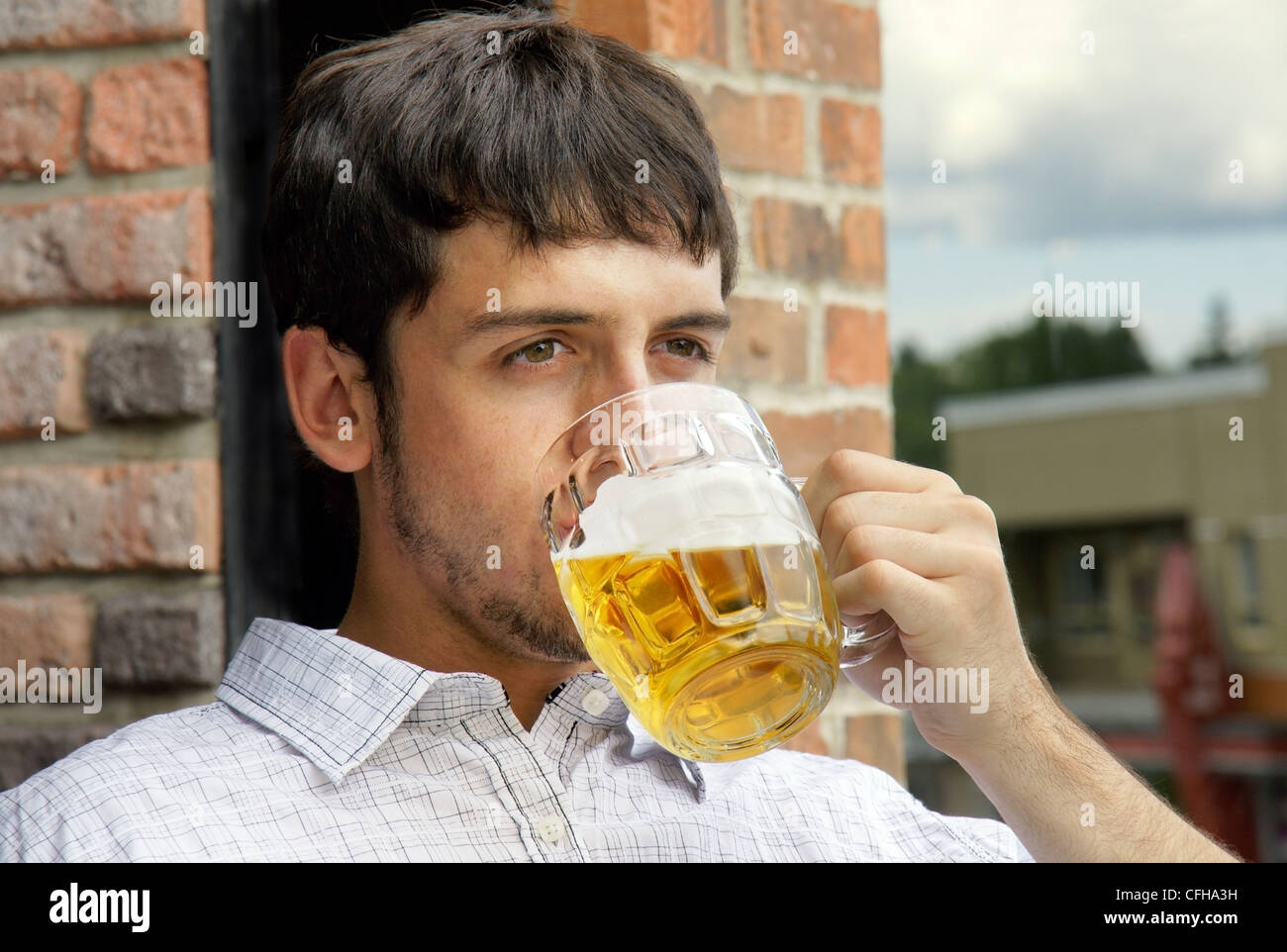Portrait of a sad young man drinking beer out of glass bok on pub's ...