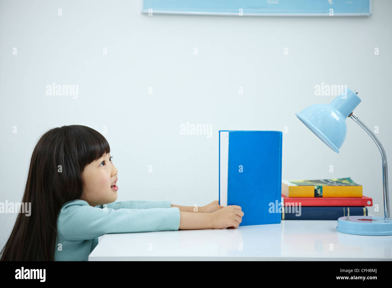 A girl reading a book in front of the desk Stock Photo - Alamy