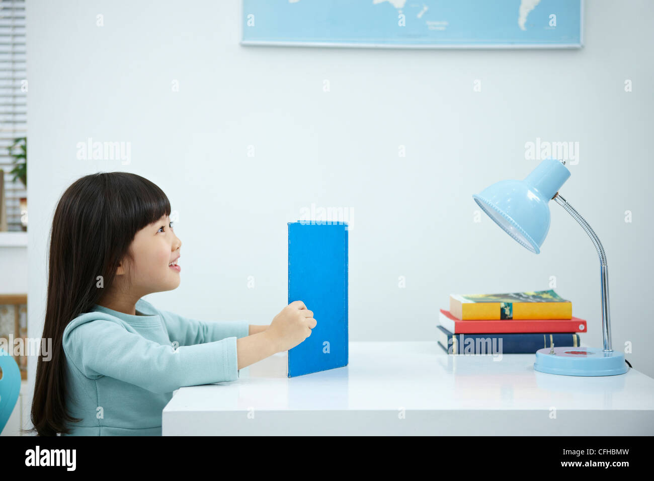 A girl reading a book in front of the desk Stock Photo - Alamy