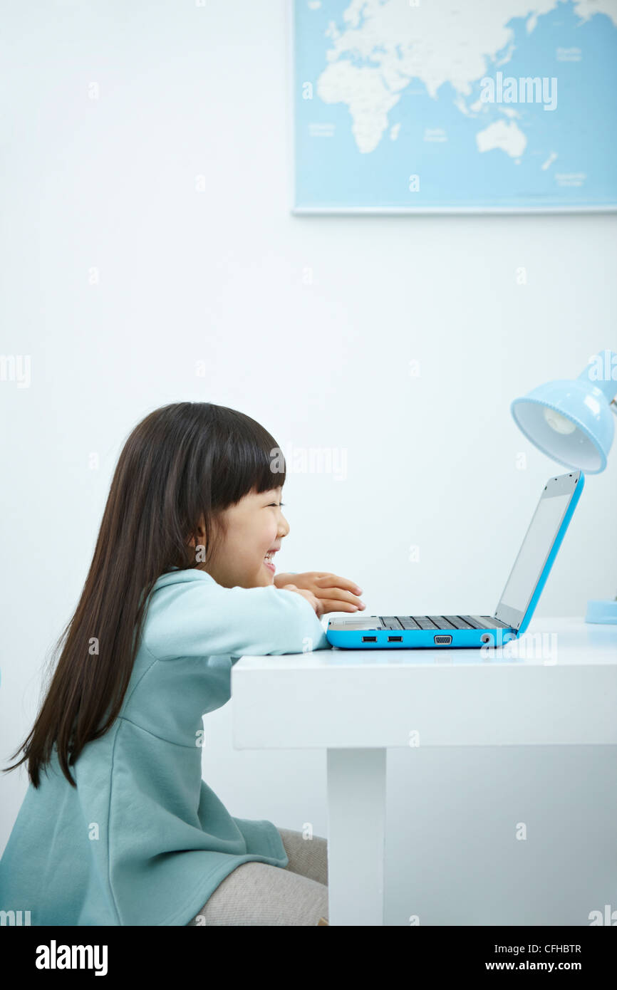 A smiling girl looking at a laptop in front of the desk Stock Photo - Alamy
