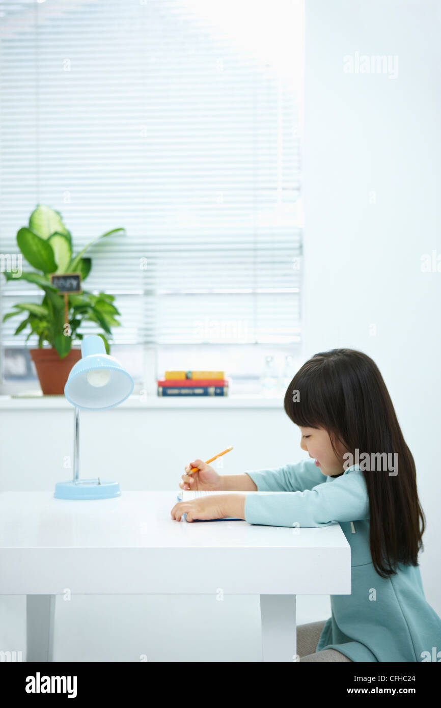 A girl reading a book with a pencil in her hand Stock Photo - Alamy