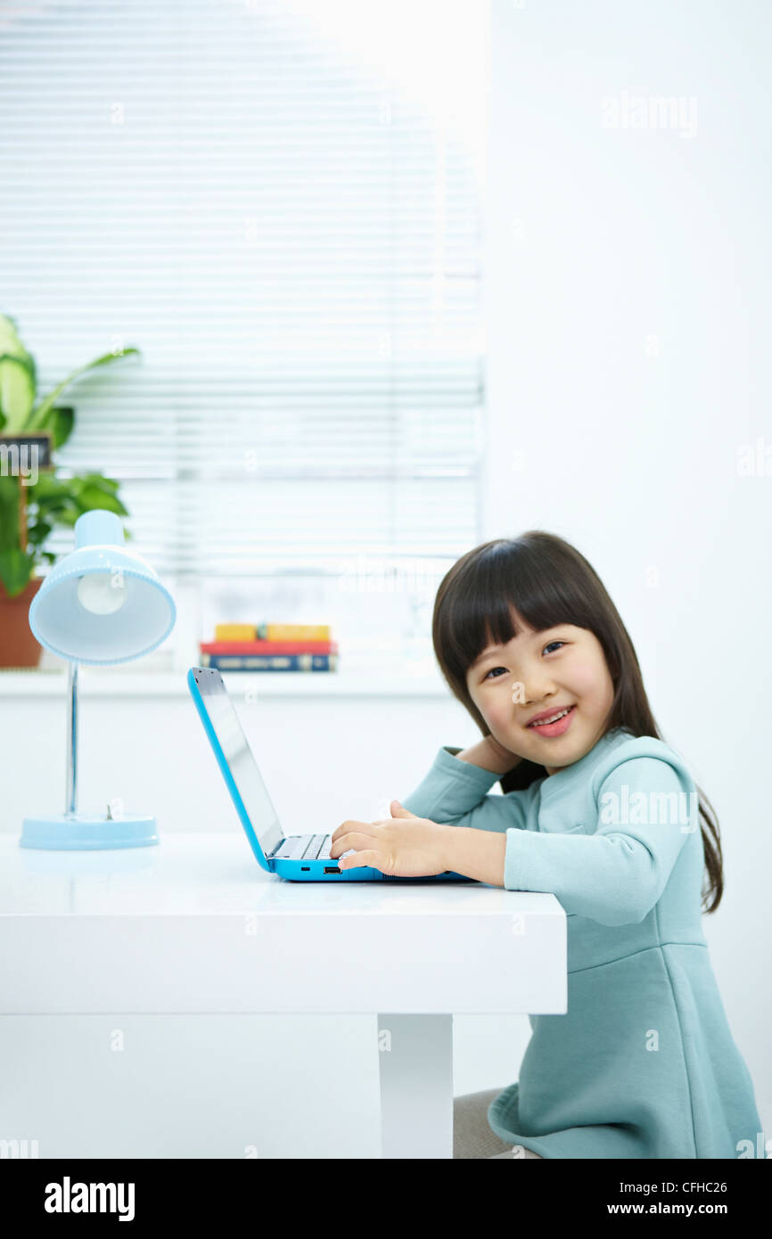 A smiling girl with a laptop on the desk Stock Photo - Alamy