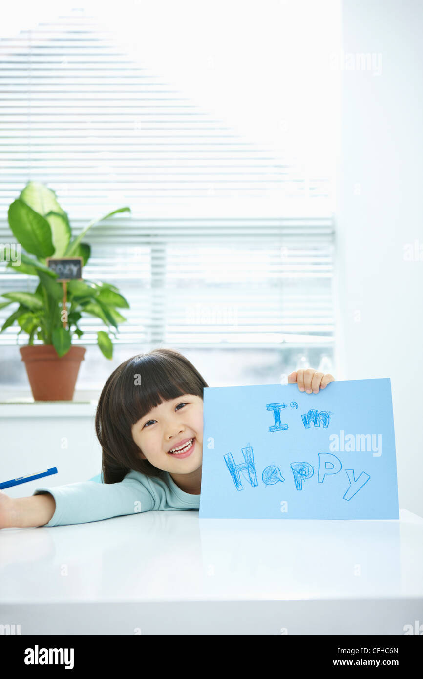 A girl showing blue paper with 'I'm happy' with a pencil in her hand ...