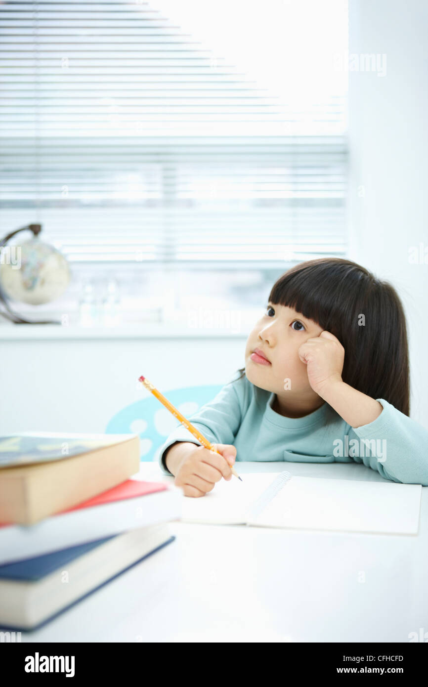 A thinking girl while holding a pencil over a note book Stock Photo - Alamy