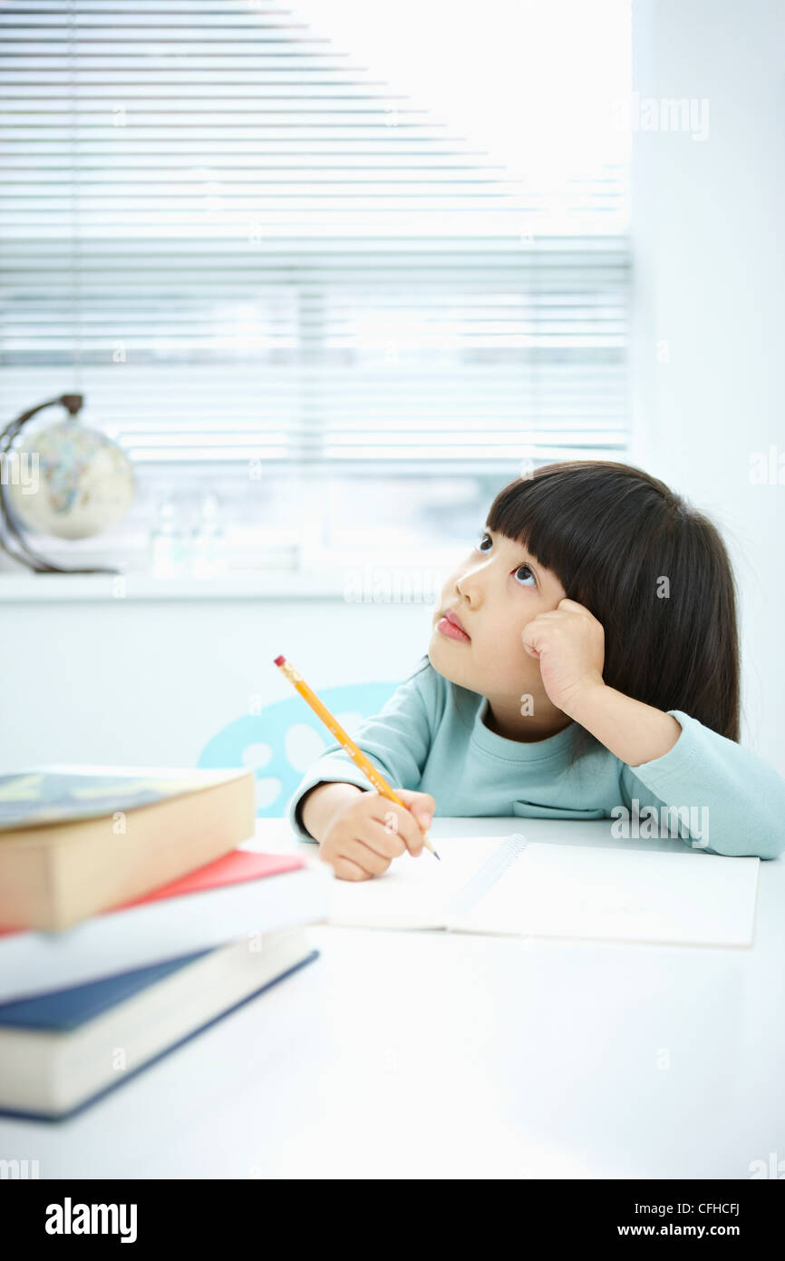 A thinking girl while holding a pencil over a note book Stock Photo - Alamy