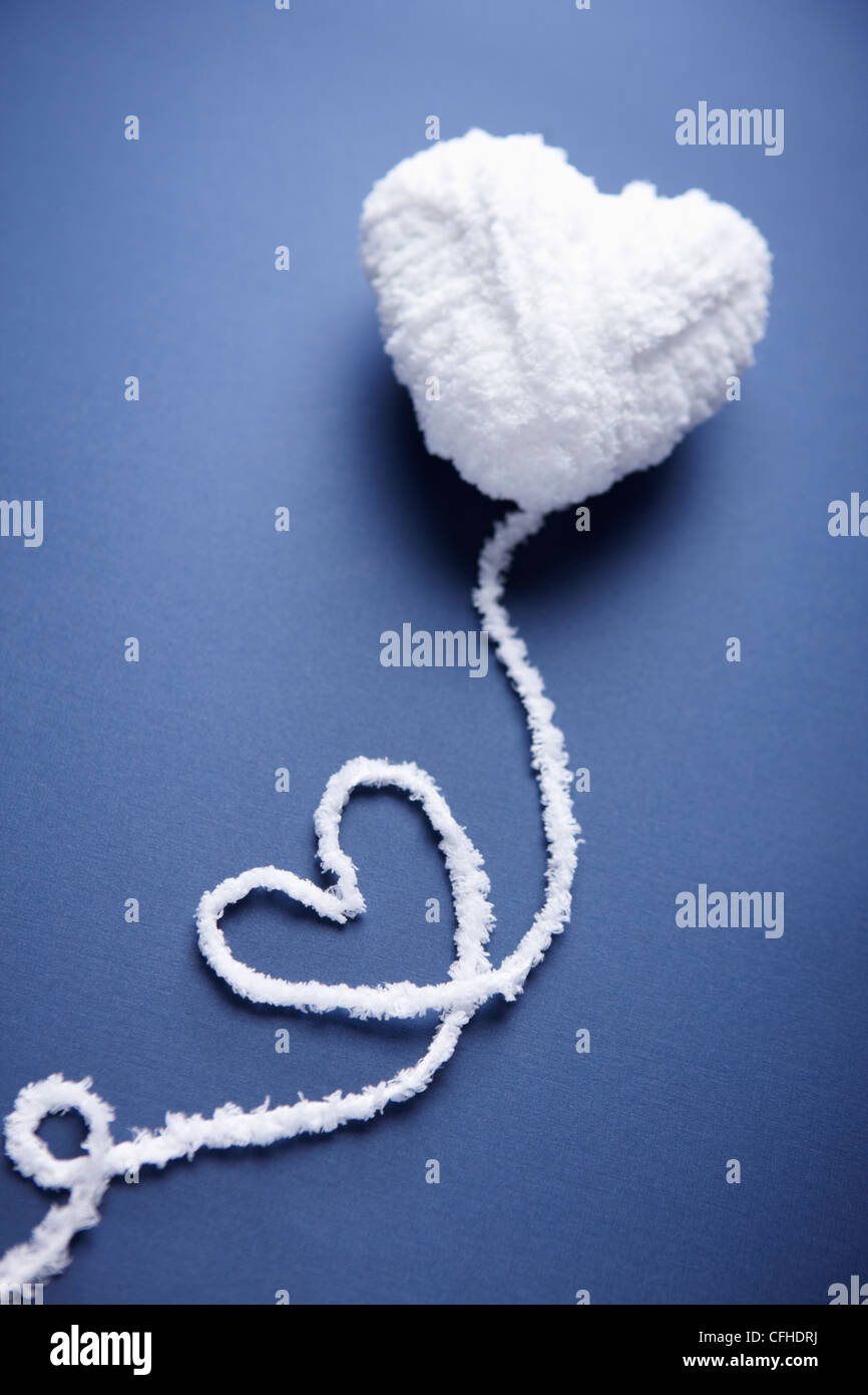A heart shaped ball of white wool with a heart shaped yarn out of it ...