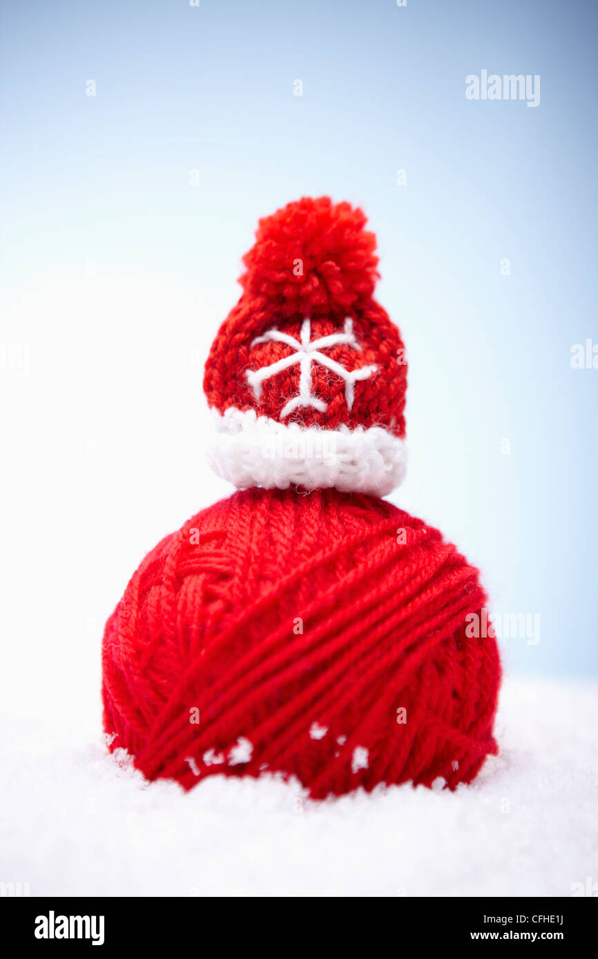 A ball of red wool and red knit hat on the snow Stock Photo - Alamy