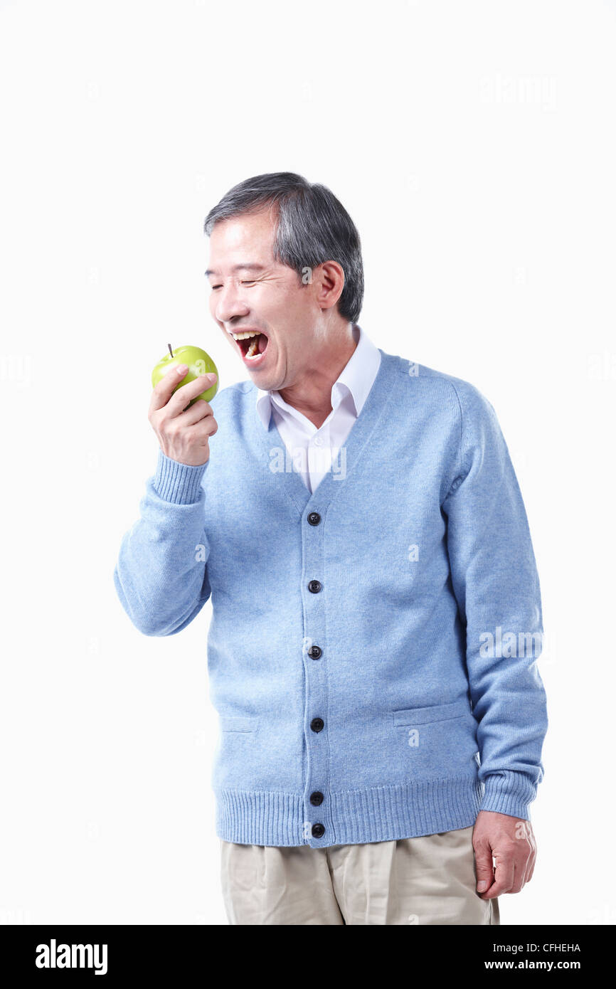 An elderly man biting an apple Stock Photo - Alamy