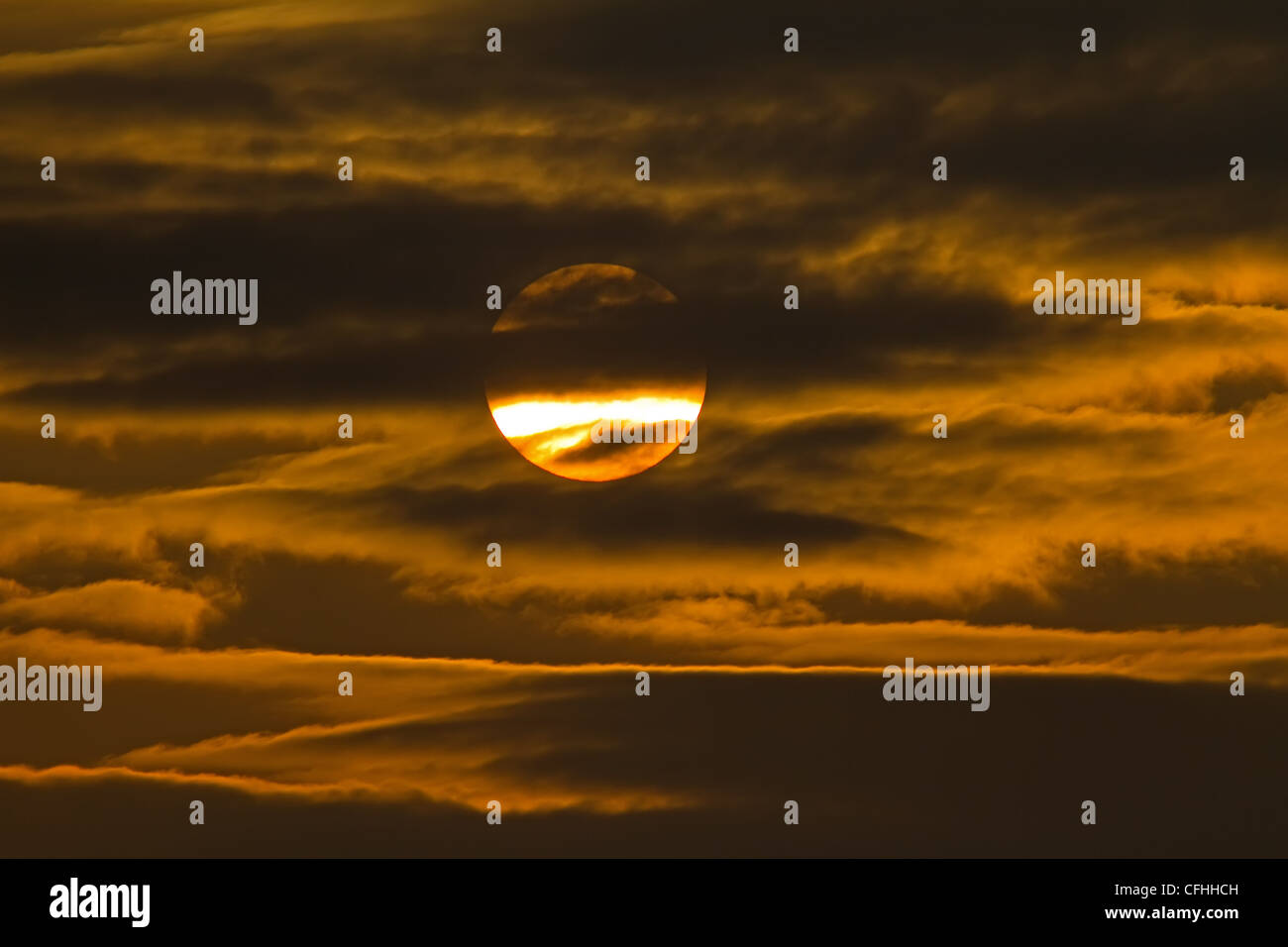 The sun behind clouds a little before setting down Stock Photo - Alamy