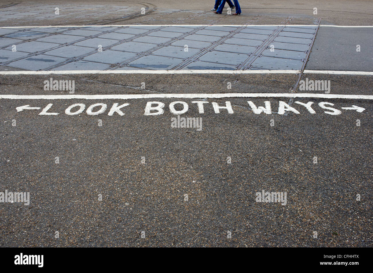 People walking past a sign painted on the ground Stock Photo - Alamy