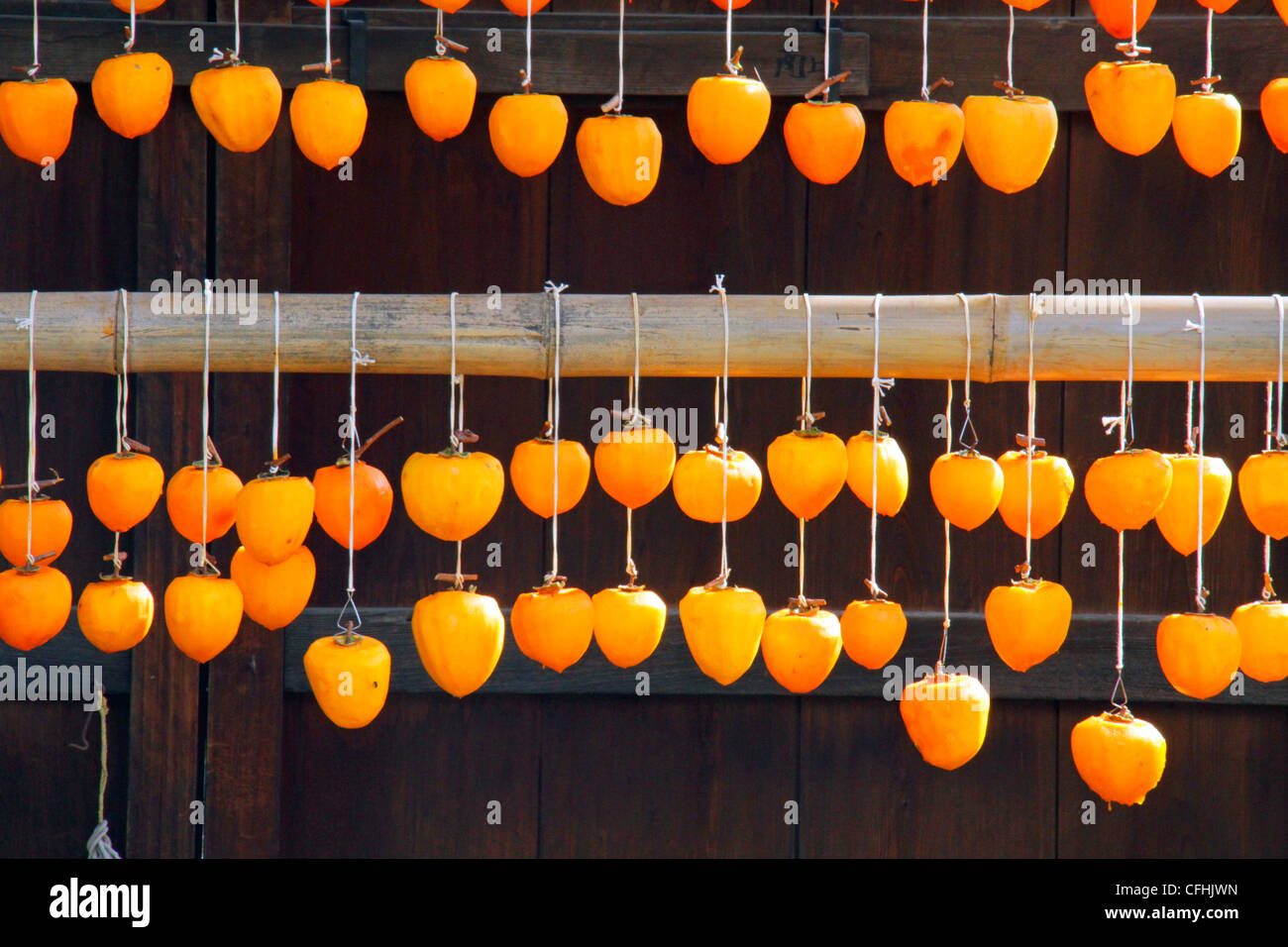 Peeled Persimmons hanging to dry under a farm house roof Japan Stock ...