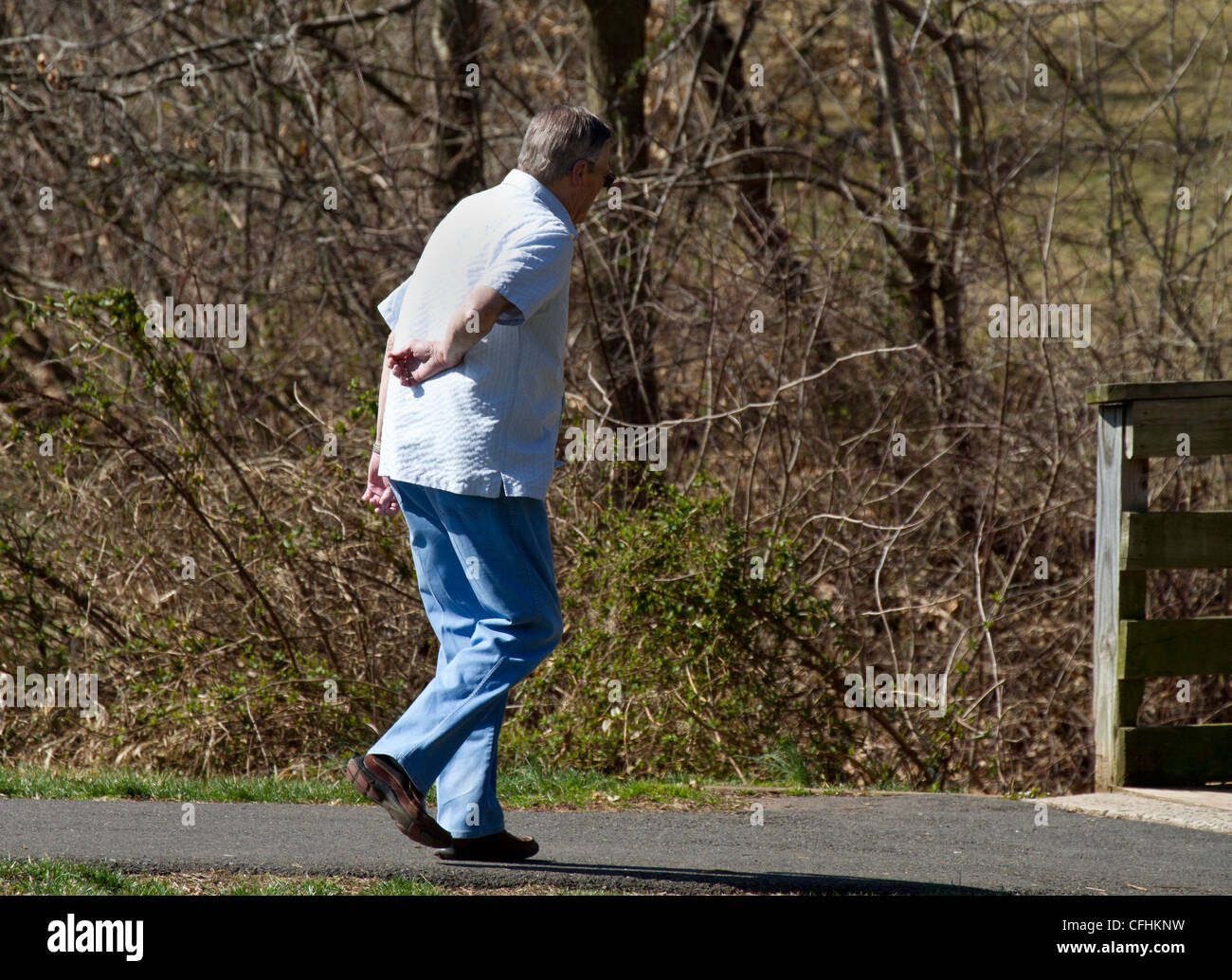 A senior man with back problems holding his back while walking Stock ...