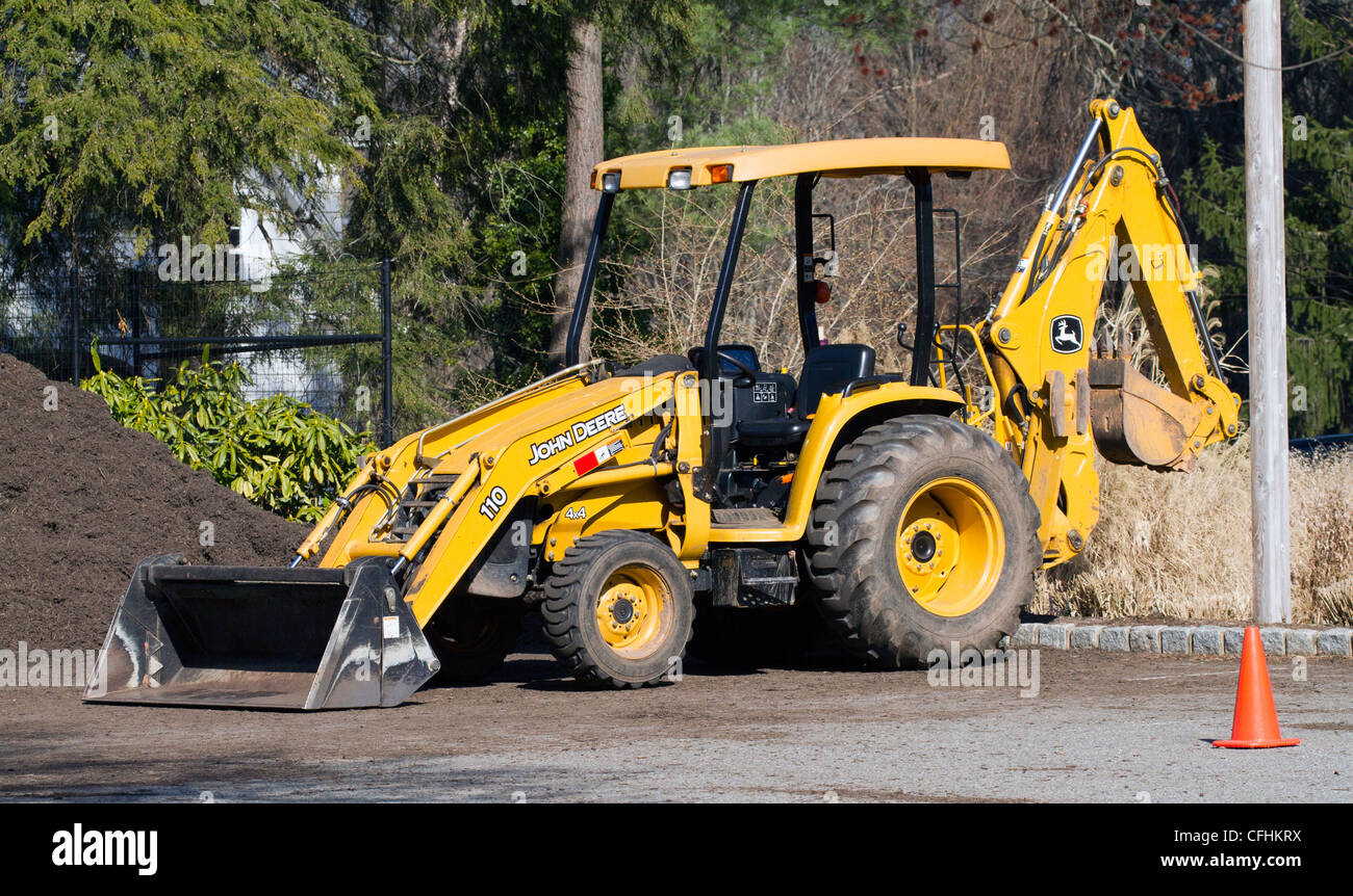 Yellow John Deere 110 tractor parked nest to a pile of mulch Stock ...