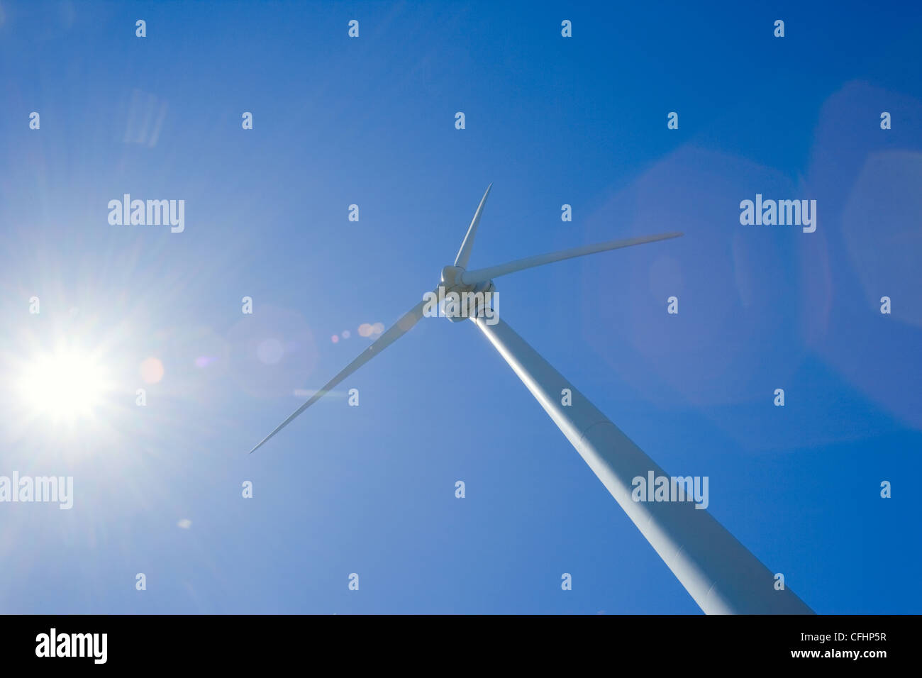 Wind turbine with the sun shining in a blue sky Stock Photo - Alamy