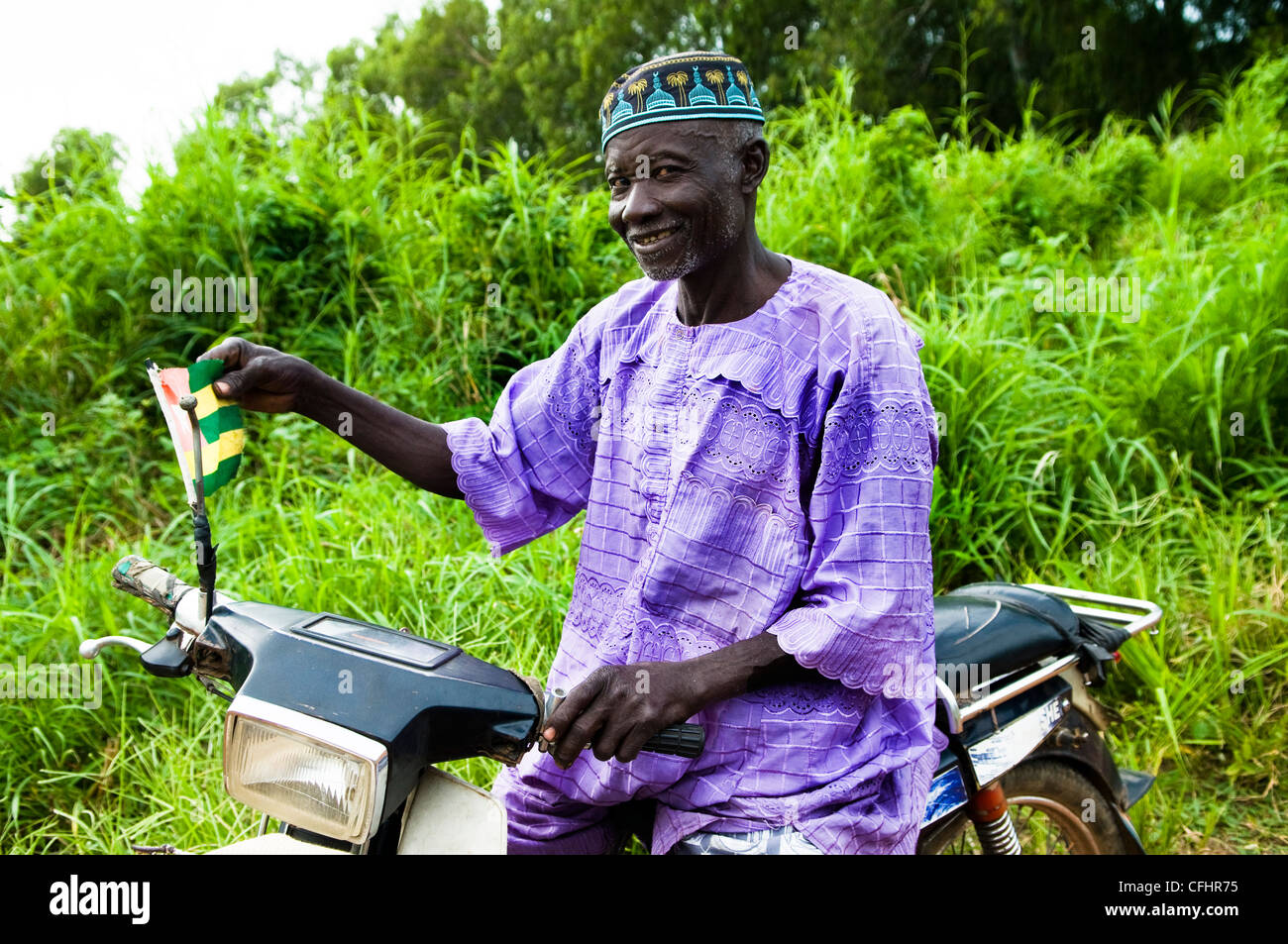 A Muslim Beninese man wearing a traditional Batik shirt and a colorful ...