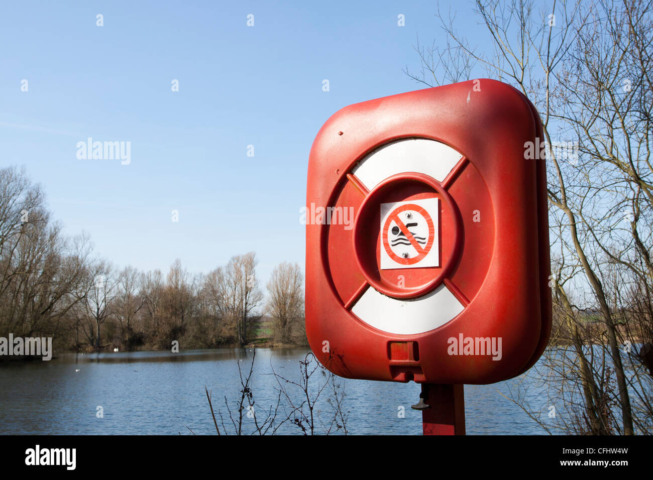 Red life saving equipment with a no swimming sign beside a pond/lake ...