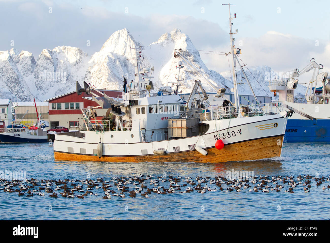 Fisherman and fishing vessels in the Myre port, surrounded by mountains ...
