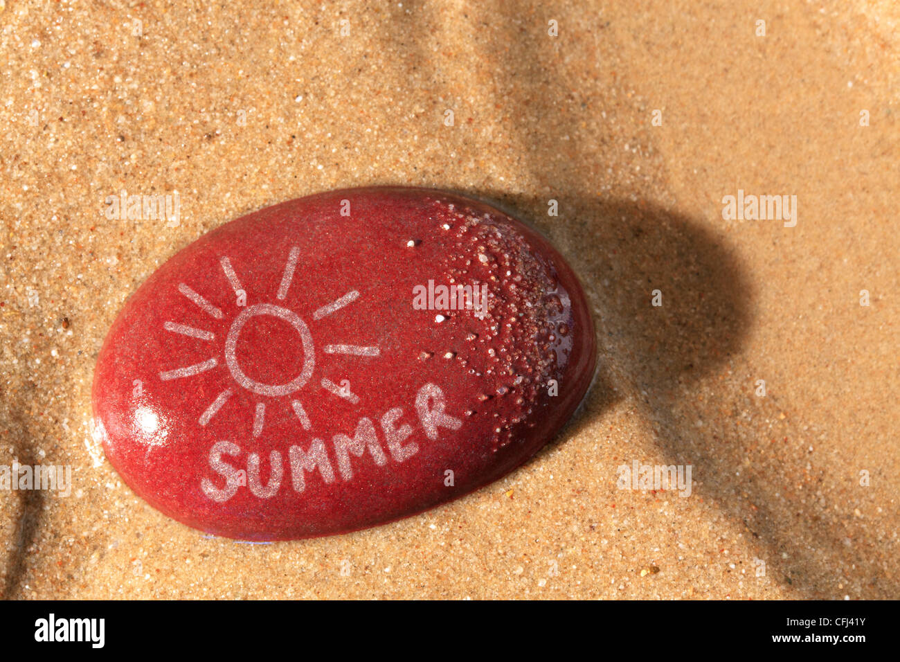 Concept photo of a wet red pebble on a sandy beach with a drawing of ...