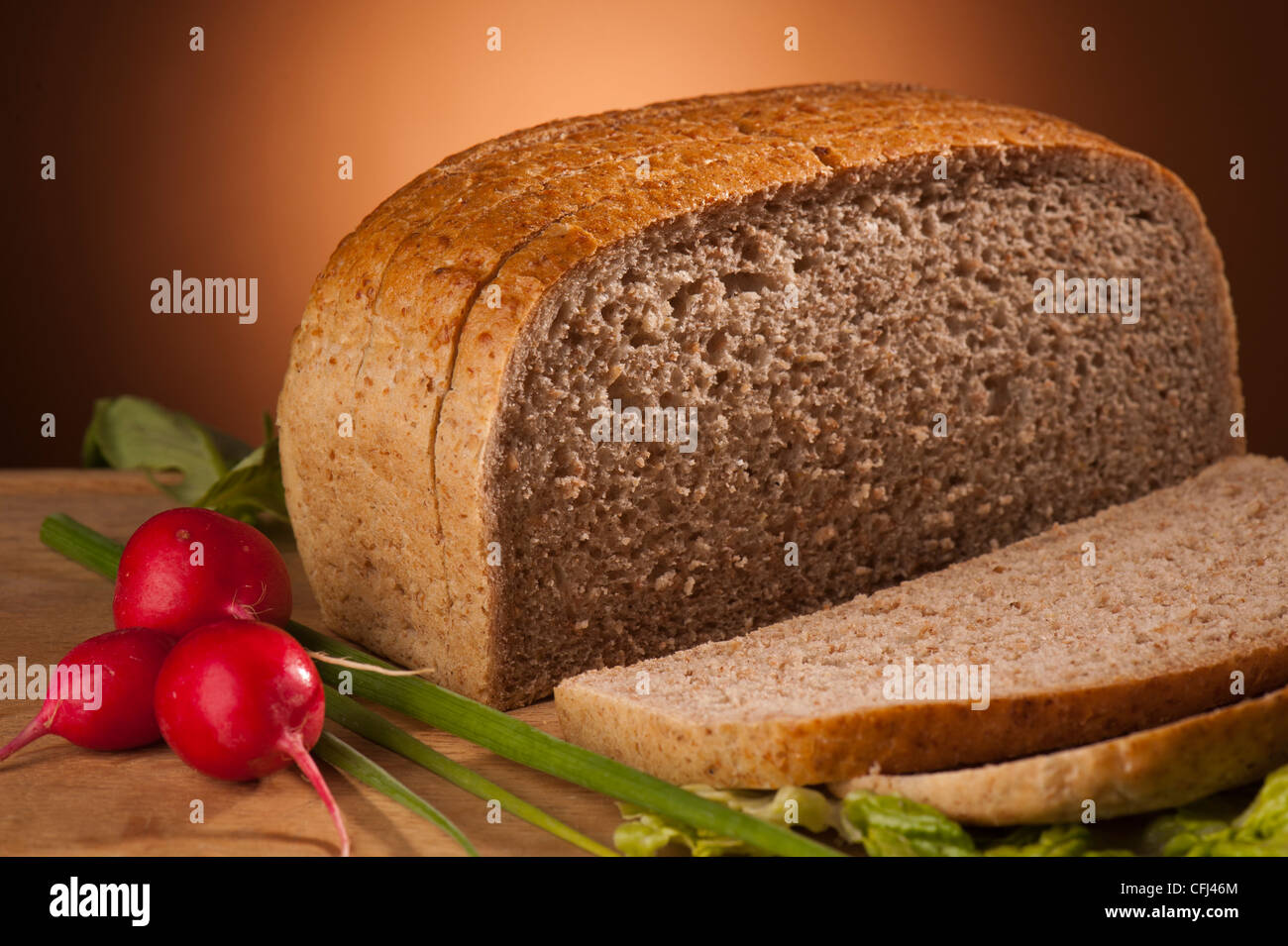 Brown wheat germ bread loave sliced on brown background Stock Photo - Alamy