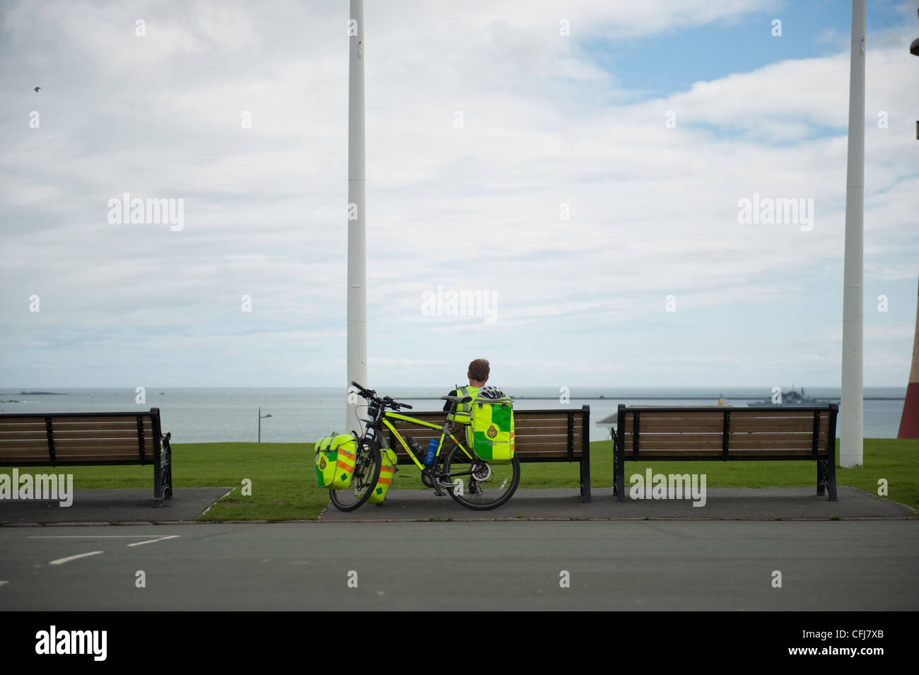 A cycle response unit man sits on a bench looking out to sea with his ...