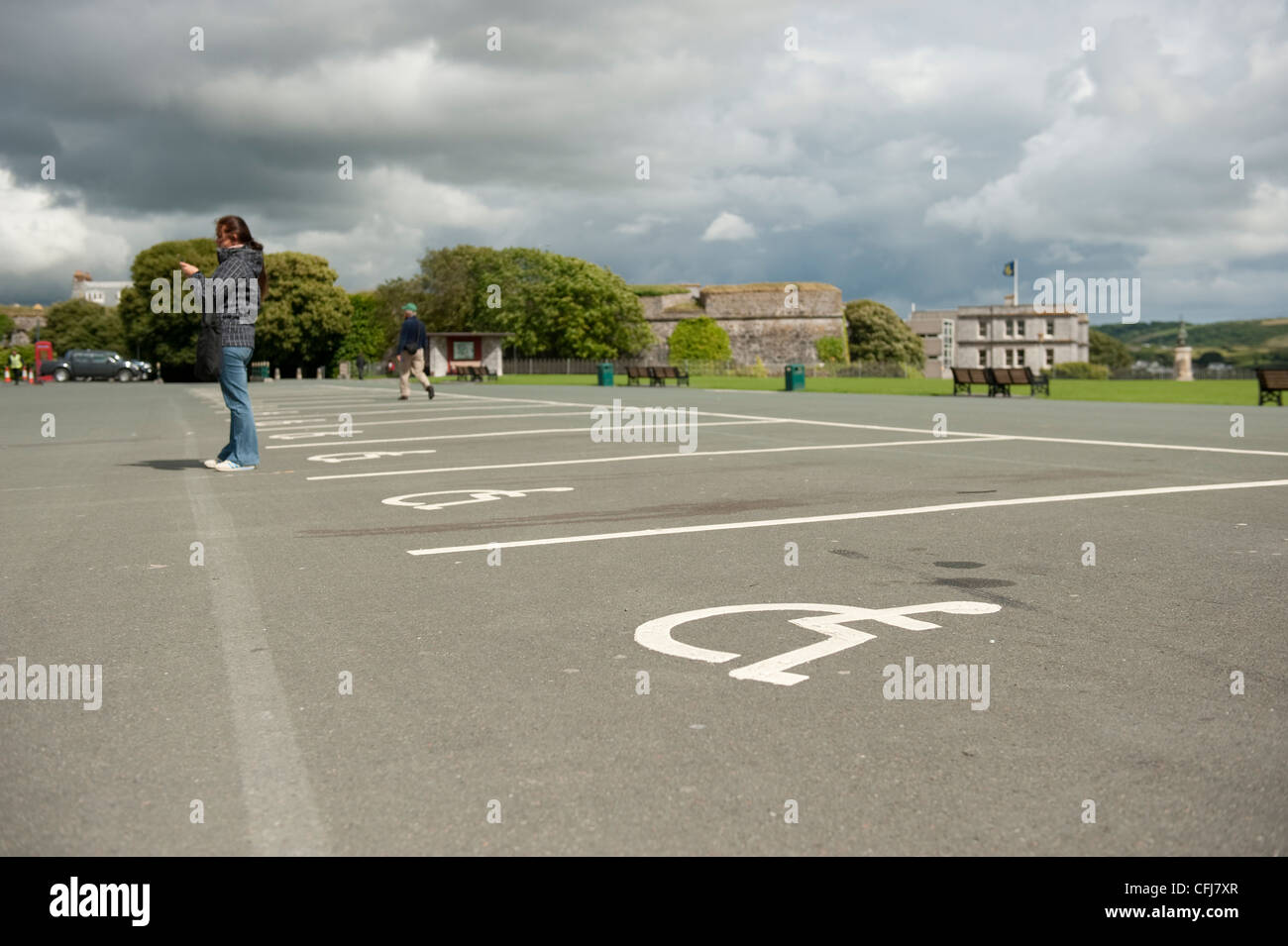 A tourist stands near an empty disabled parking space marked by a ...