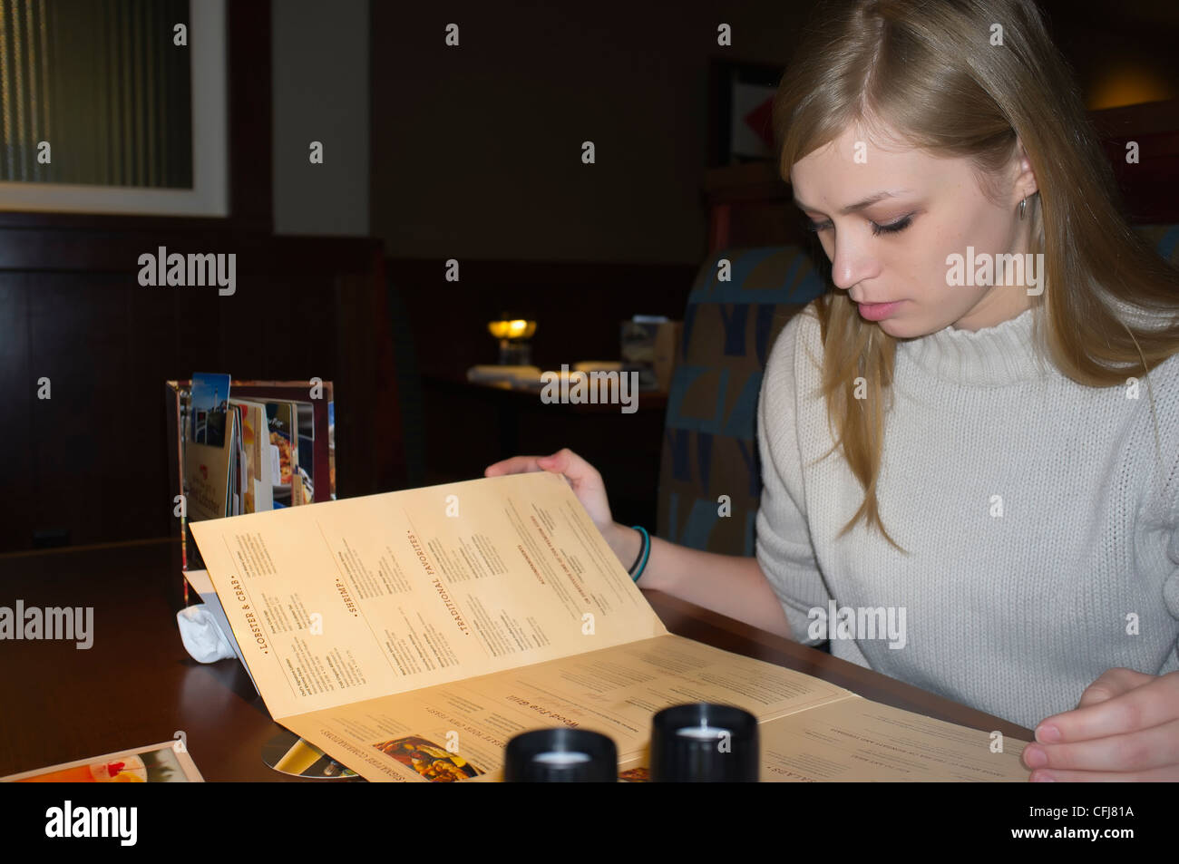 Young woman reading menu at restaurant table - ready to order dinner ...