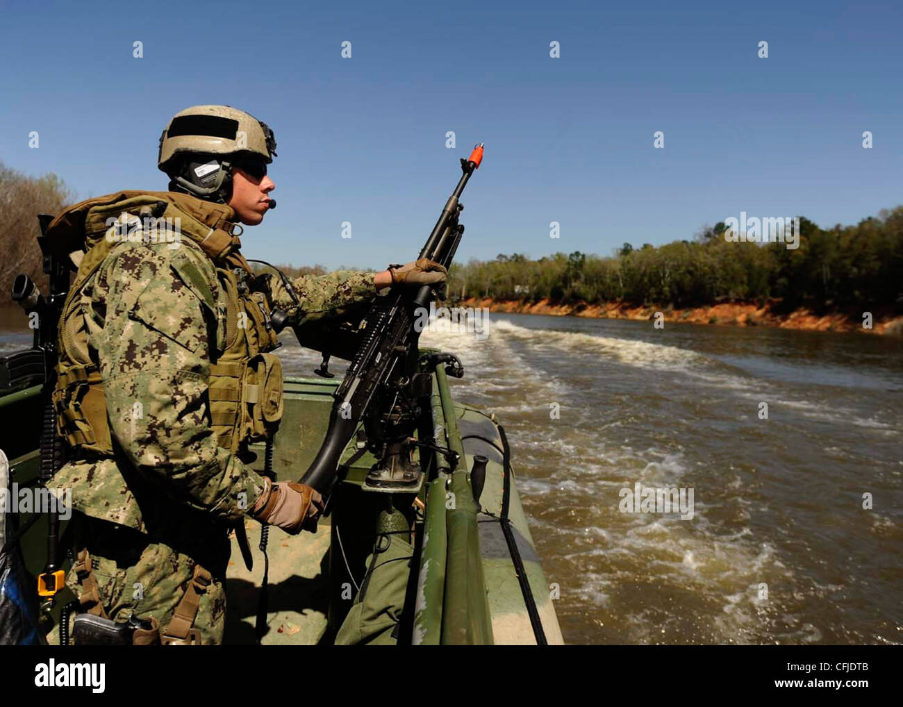 A U.S. Navy boat gunner loads a 245 machine gun during Emerald Warrior ...