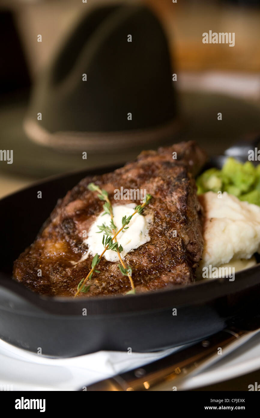 Sizzling T-Bone steak served in cast iron with mashed potatoes and ...