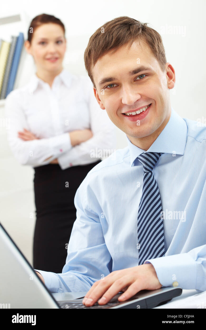 Portrait of happy man at workplace touching keys of laptop Stock Photo ...