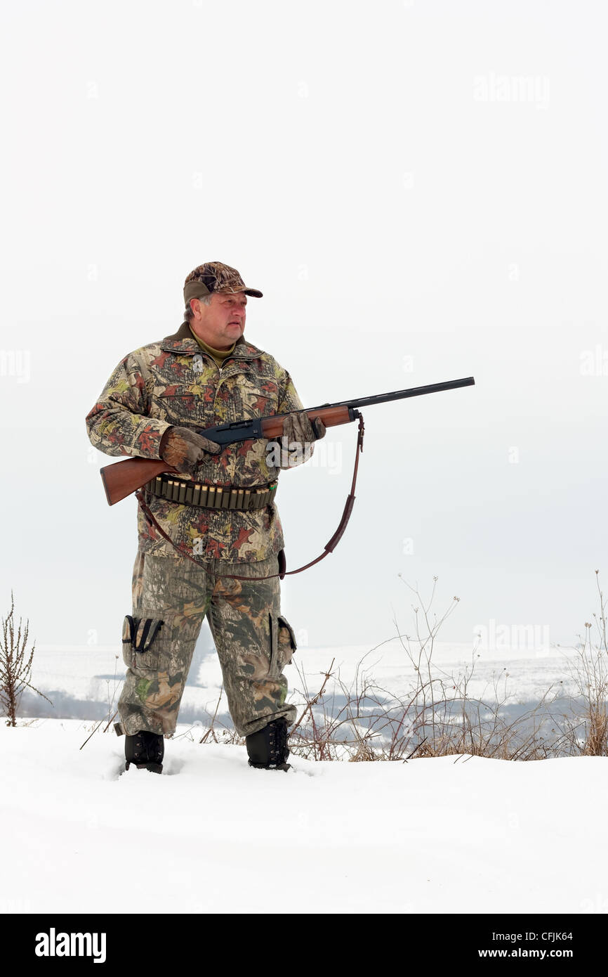 Male hunter in camouflage,holding his gun and looking for his target or ...
