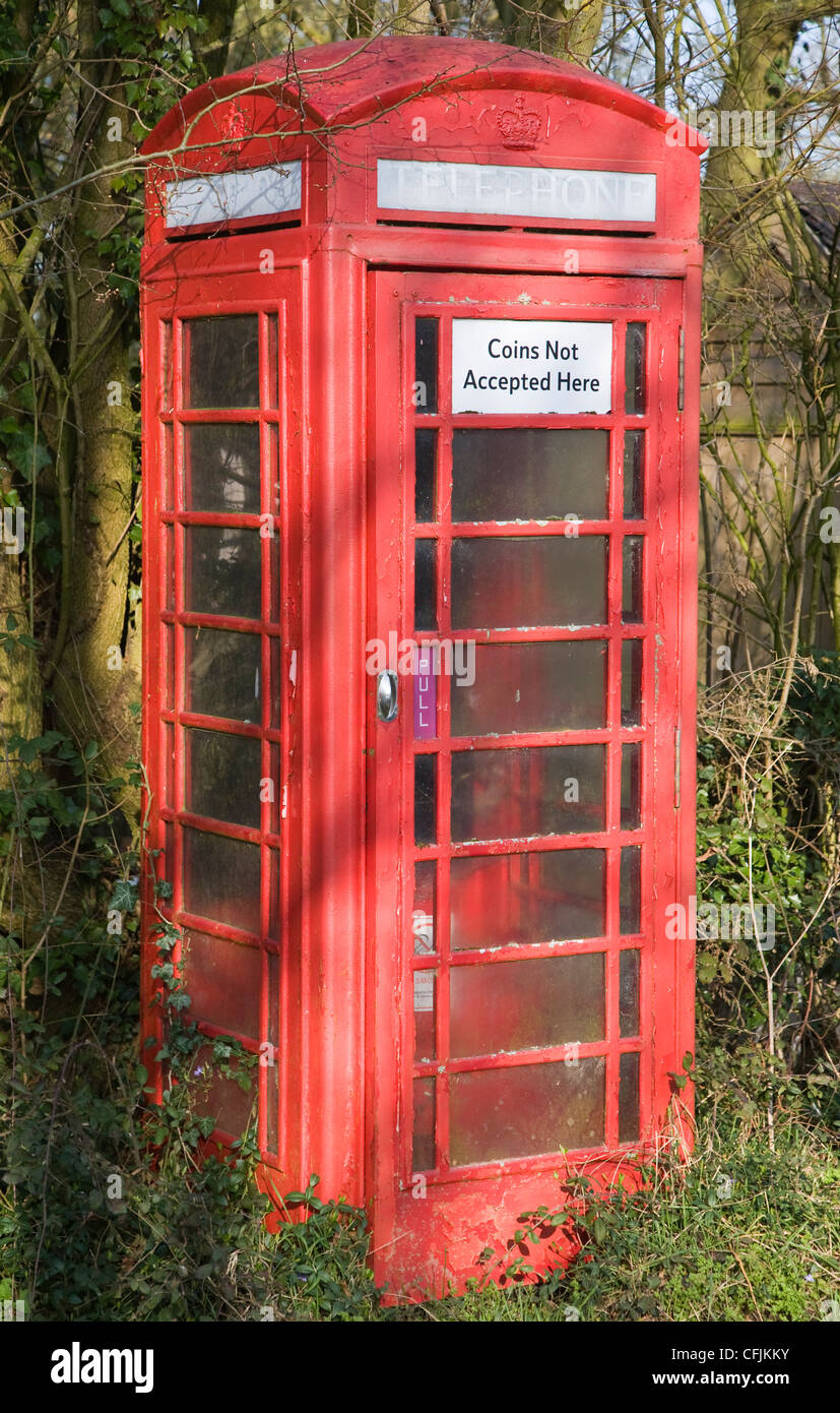 Traditional red telephone box in rural area with sign saying coins not ...