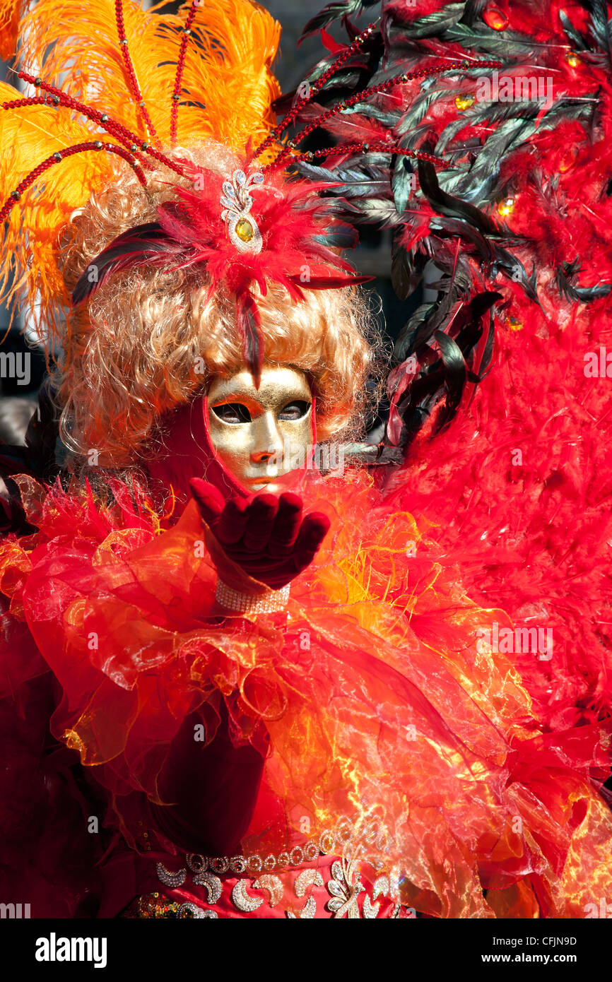 Person dressed up in orange and red carnival costume blowing a kiss at ...