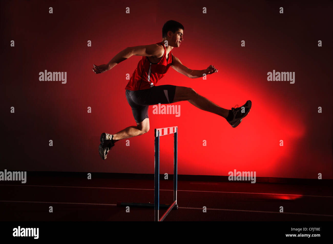 athlete running hurdles isolated on red background Stock Photo - Alamy