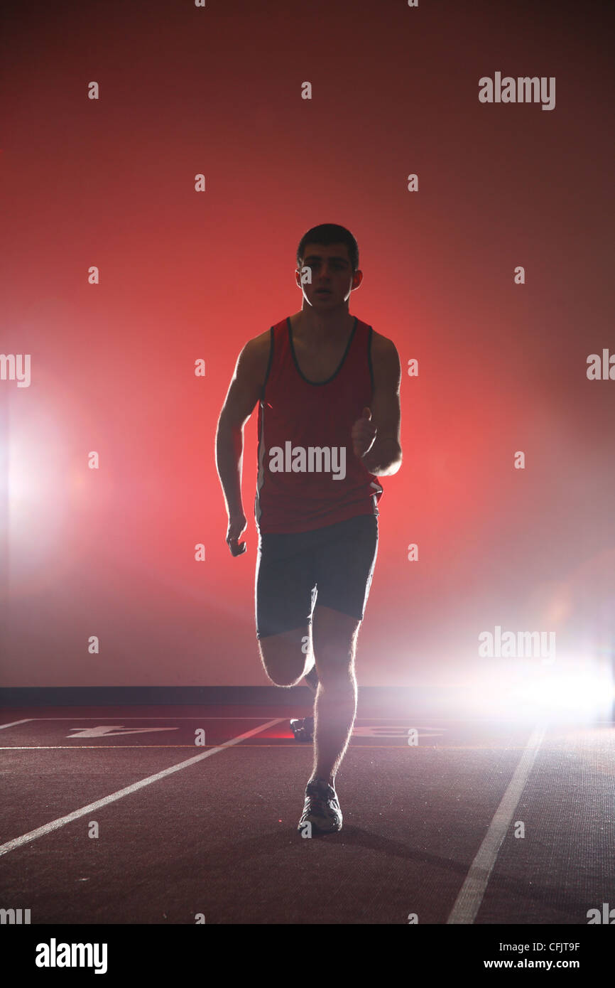 Athlete running on running track red background Stock Photo - Alamy