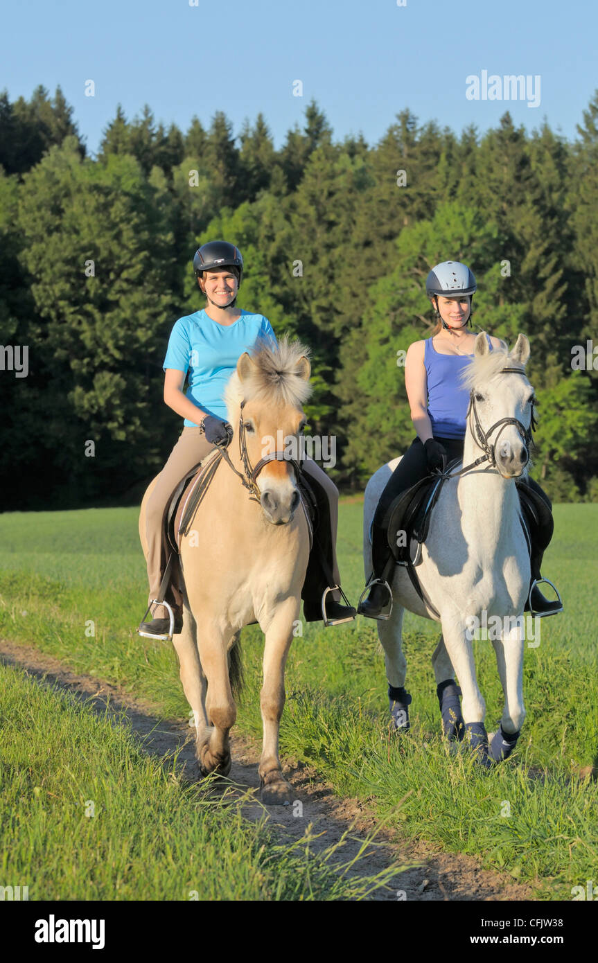 Two girls riding on back of ponies Stock Photo - Alamy