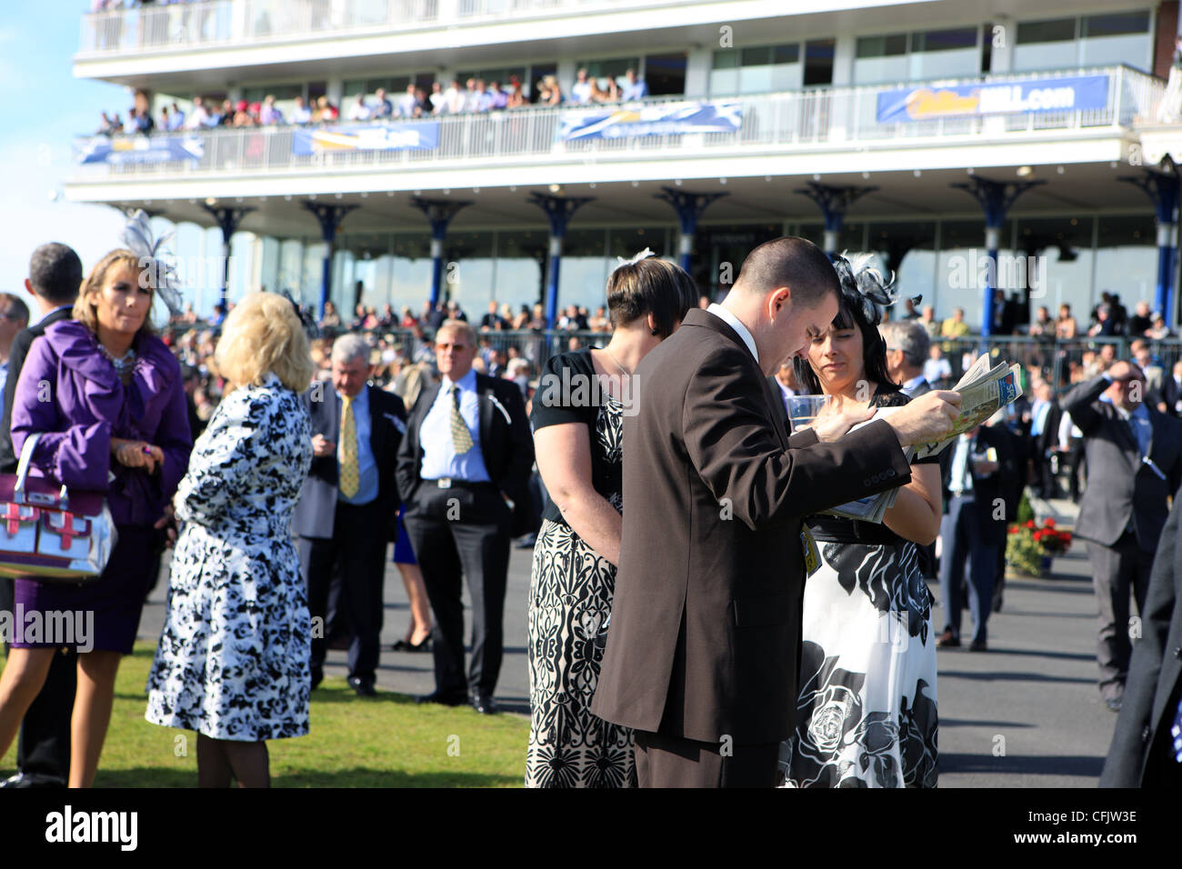 Crowds milling around reading the form before the start of a horse race ...