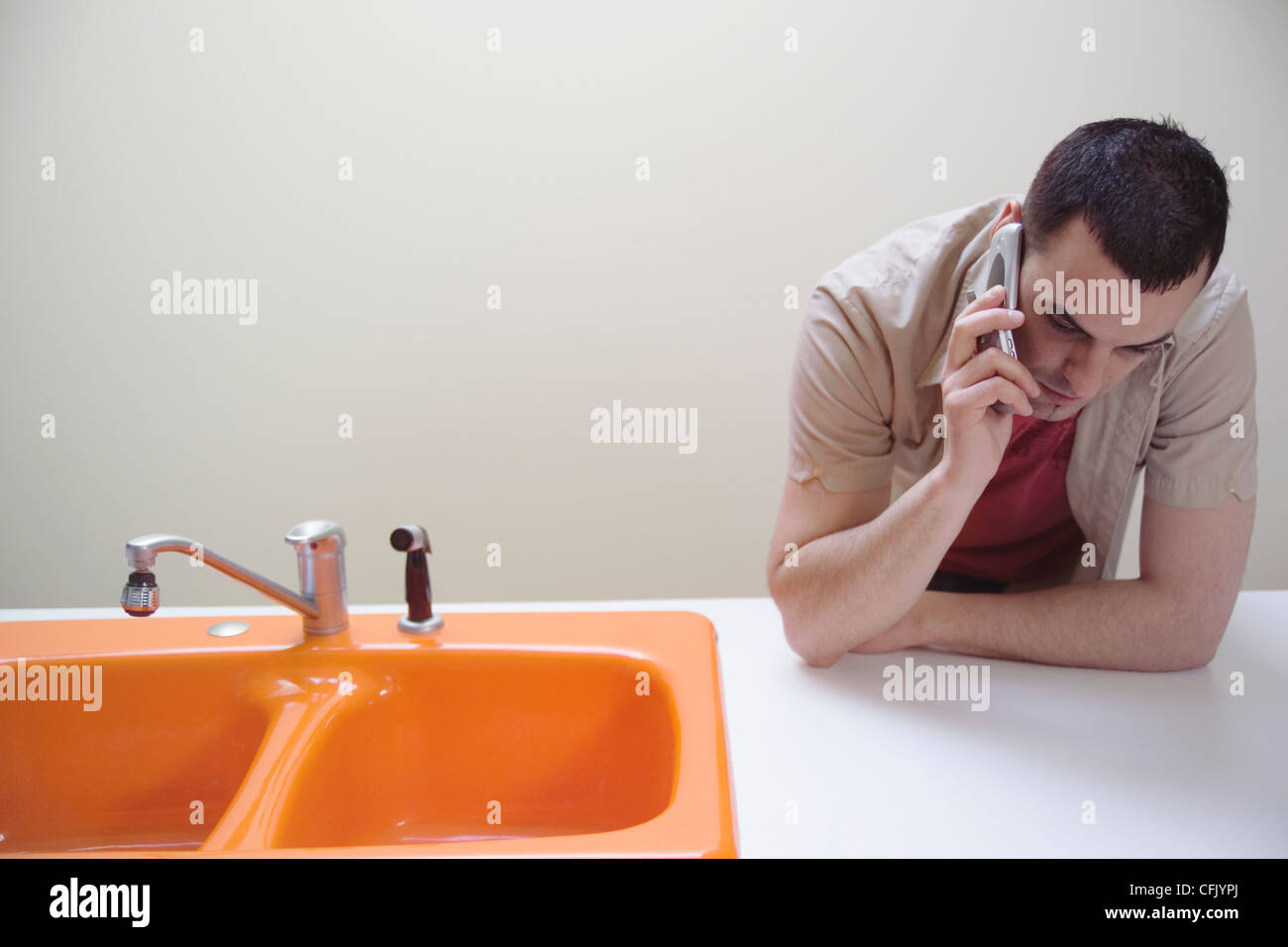 Man Leaning on Counter While on Cell Phone Stock Photo - Alamy