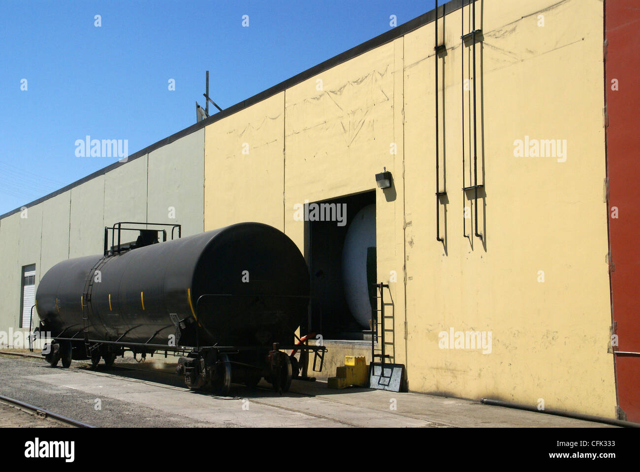 Black tank car, on railroad siding by pastel colored warehouse. Seattle ...