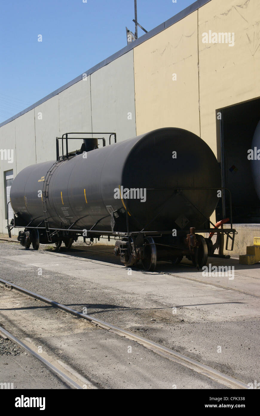 Black tank car, on railroad siding by pastel colored warehouse. Seattle ...