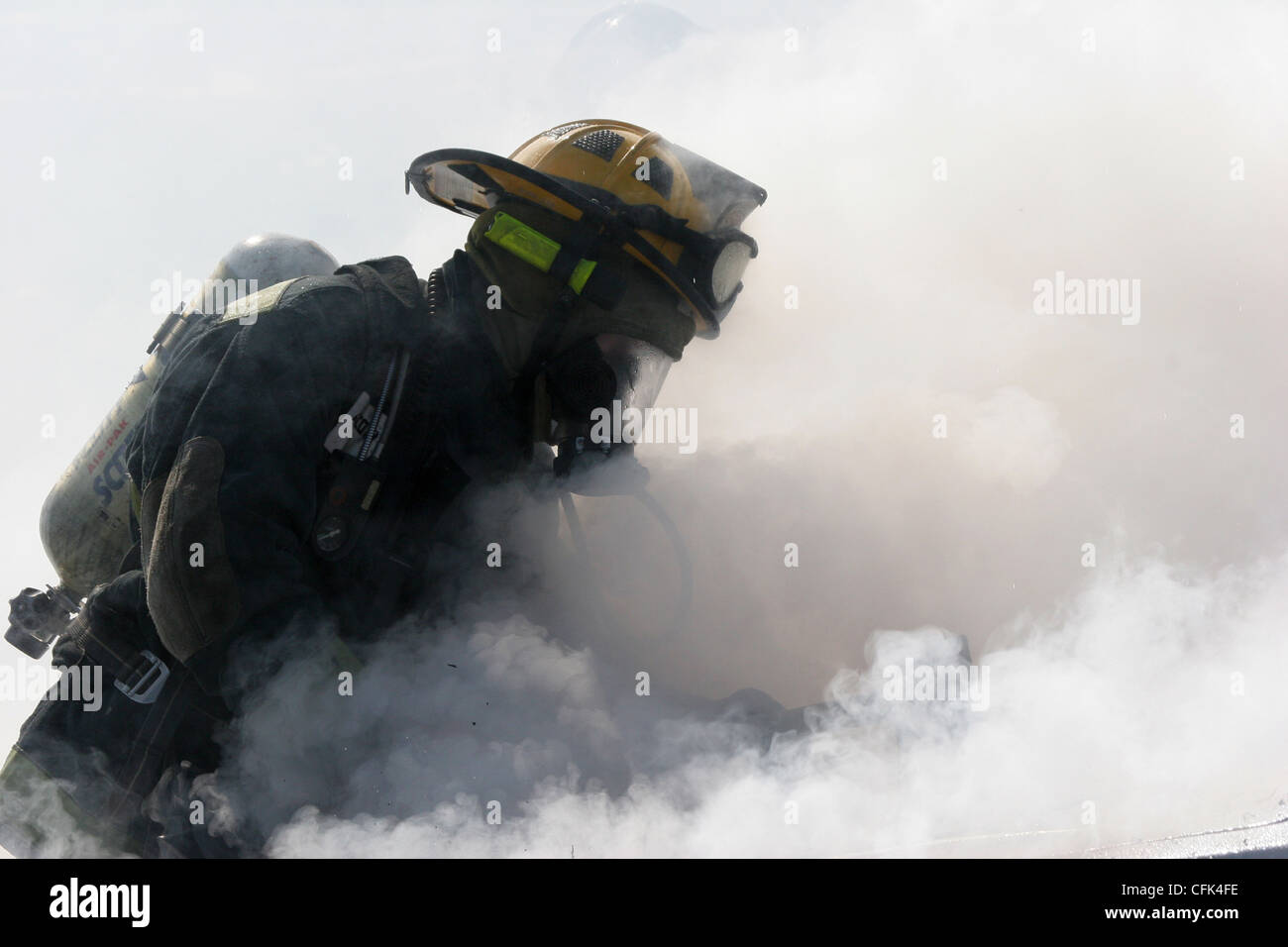 A fire fighter in smoke and steam from a car fire Stock Photo - Alamy