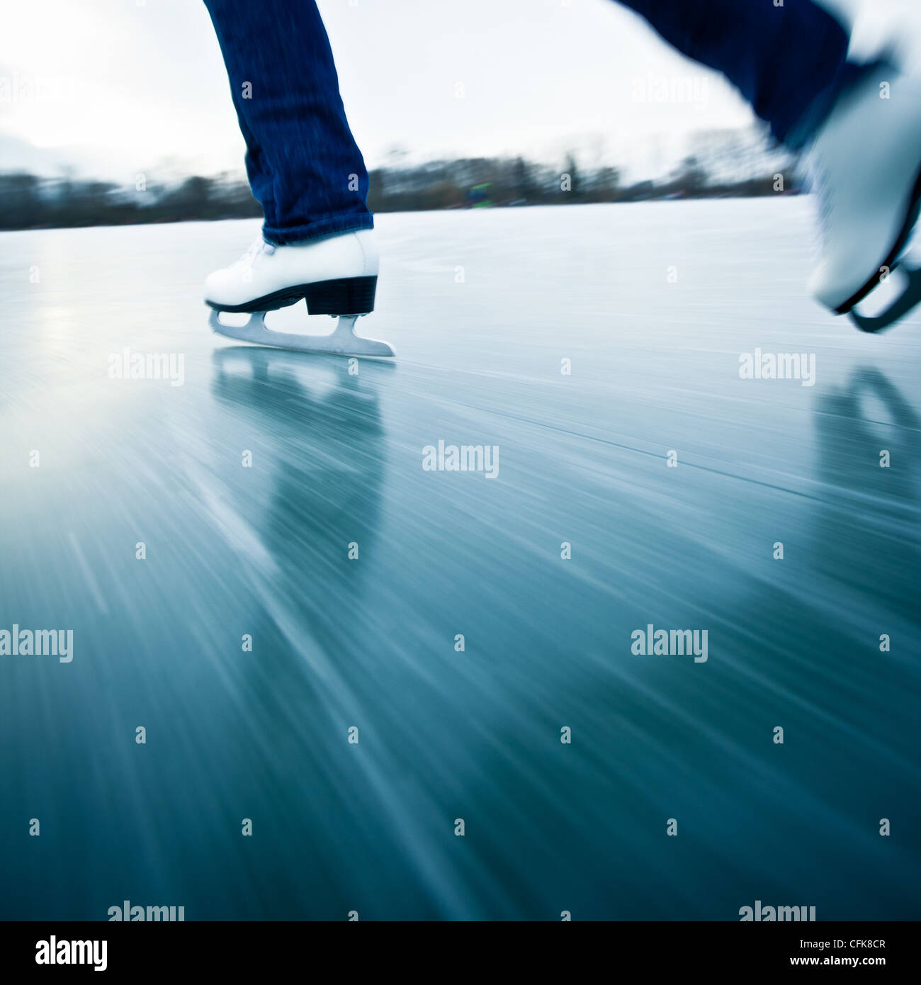 Young woman ice skating outdoors on a pond on a freezing winter day ...