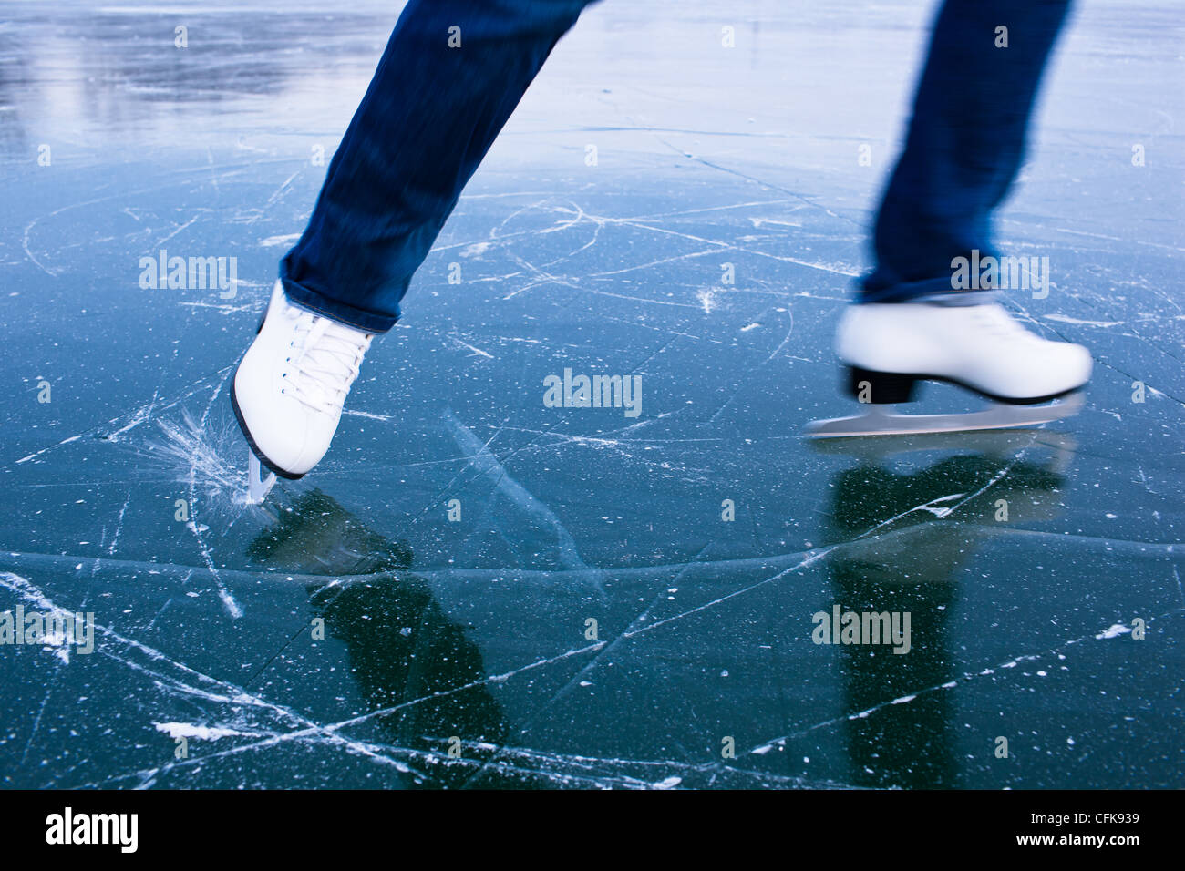 Young woman ice skating outdoors on a pond on a freezing winter day ...
