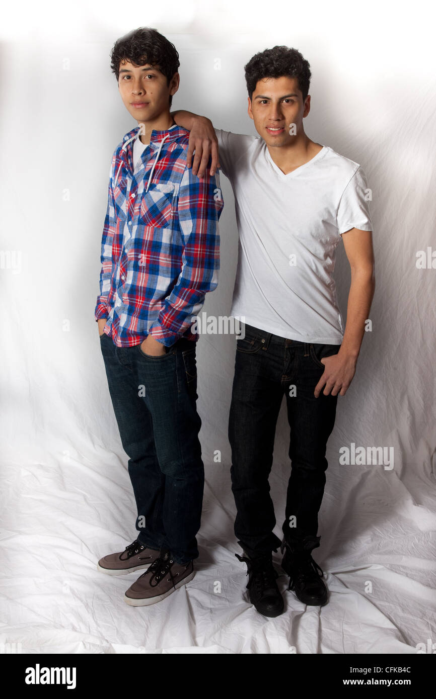 Two Hispanic brothers standing casually together and looking at the ...