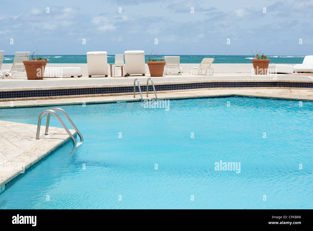 An empty outdoor swimming pool on the horizon beside the sea with ...