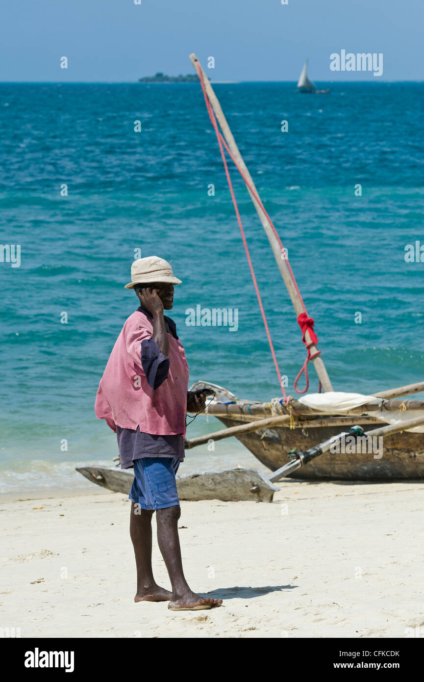 Fisherman making a phone call with his handy on the beach in Stone Town ...