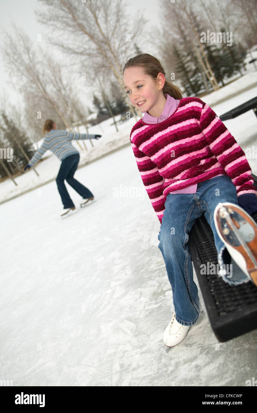 Girl on Bench with Skate Up at Outdoor Ice Rink Stock Photo - Alamy