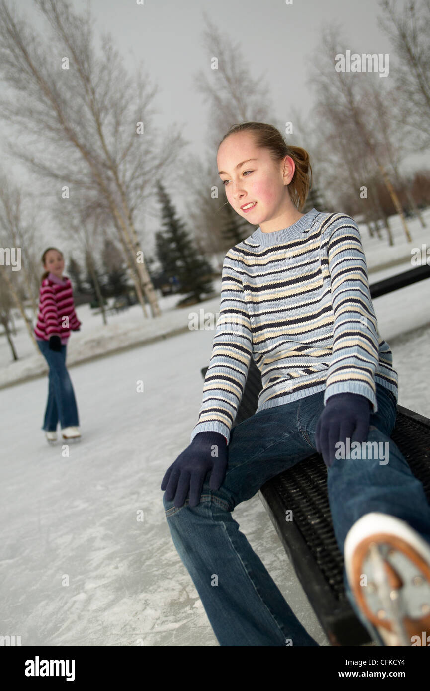 Girl on Bench with Skate Up at Outdoor Ice Rink Stock Photo - Alamy