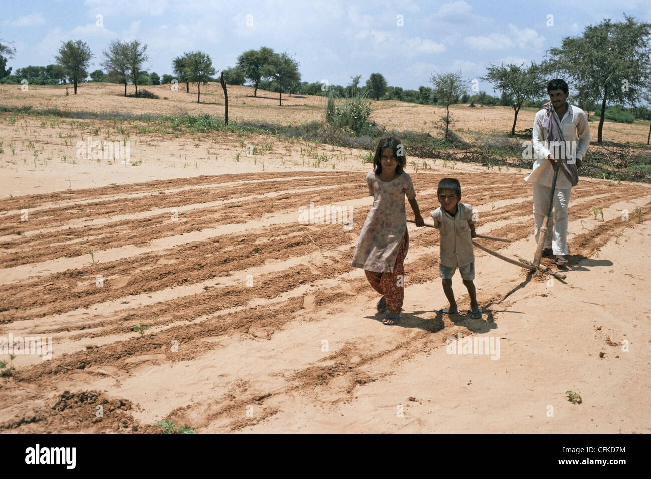 Two children are pulling a plough while a man is directing them ( India ...