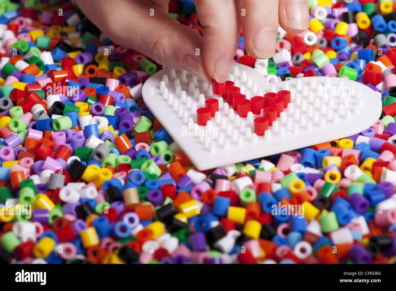 Little blond girl playing with Hama beads Stock Photo - Alamy