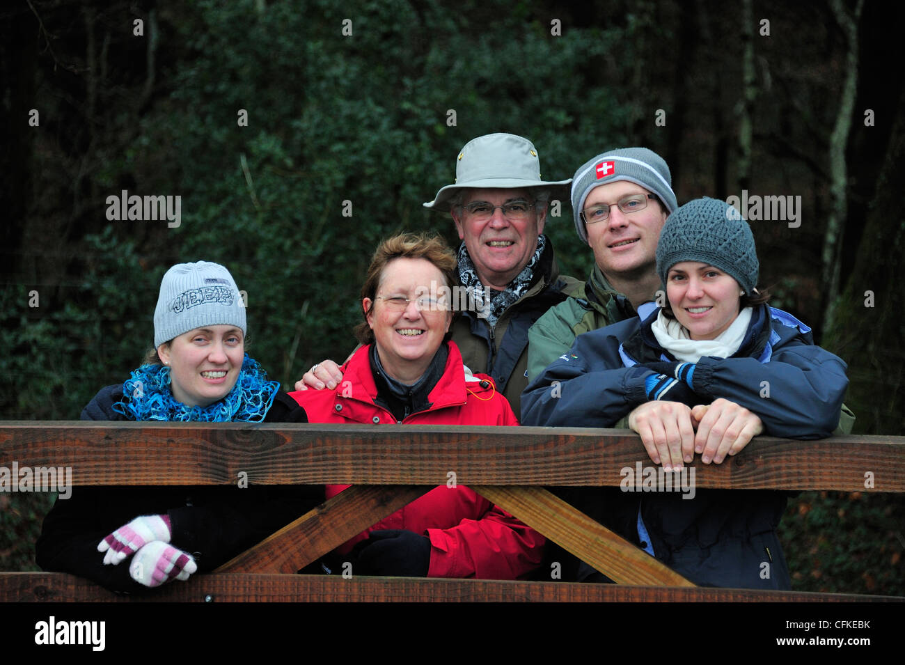 Family looking over a gate. Space for copy against the dark woodland ...